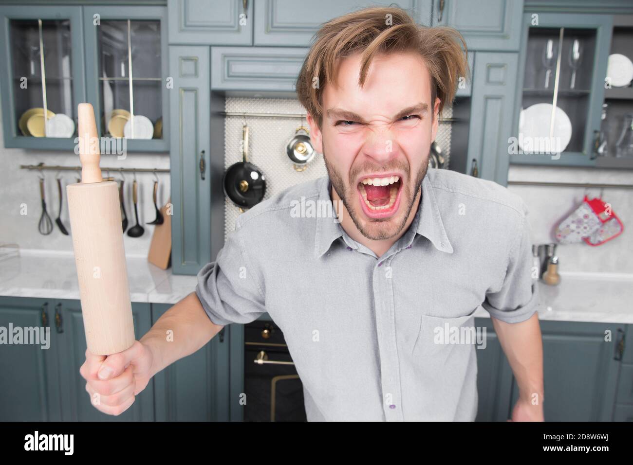 Man with angry face shout with rolling pin in kitchen. Cook, bake, home ...