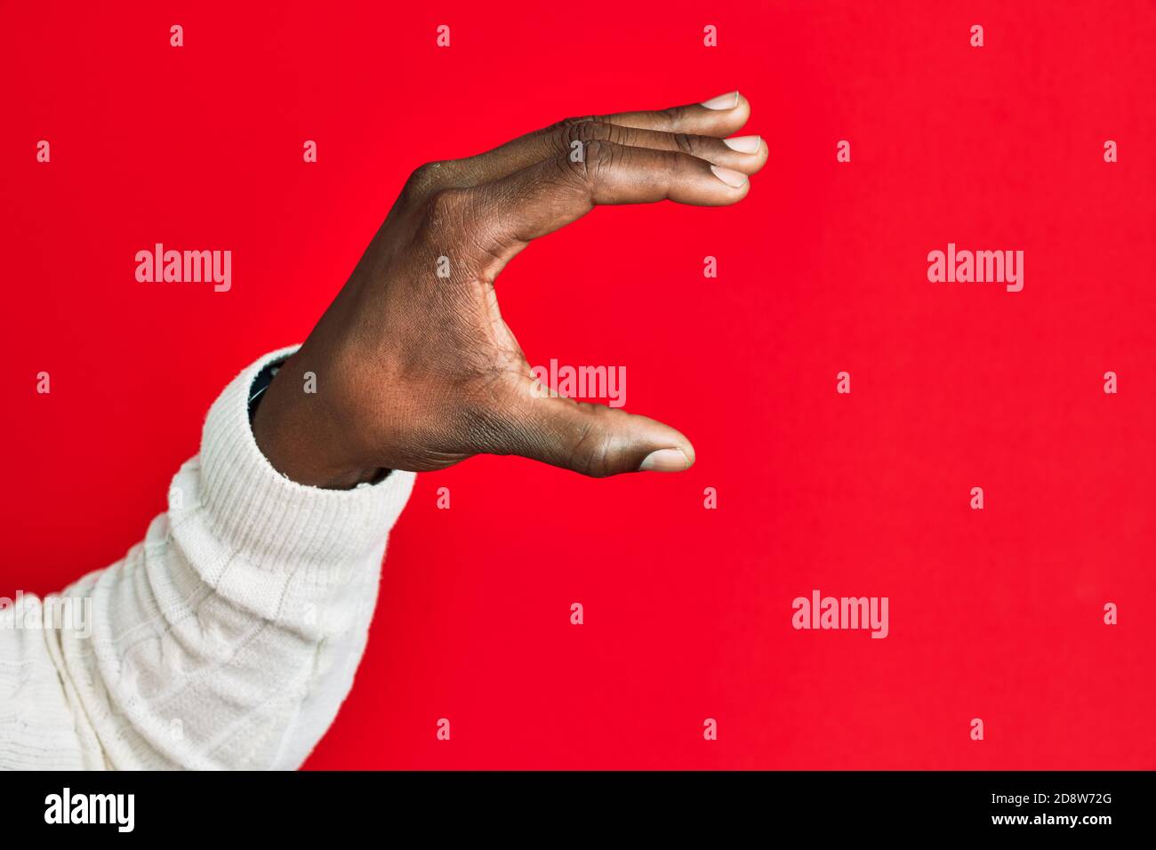 Arm and hand of african american black young man over red isolated ...