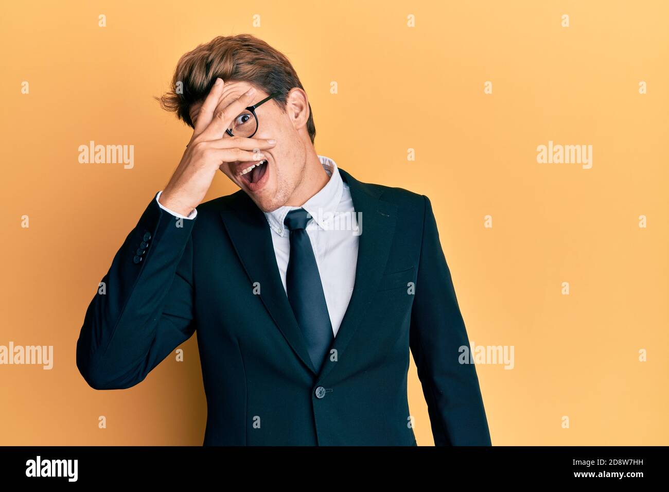 Handsome caucasian man wearing business suit and tie peeking in shock ...