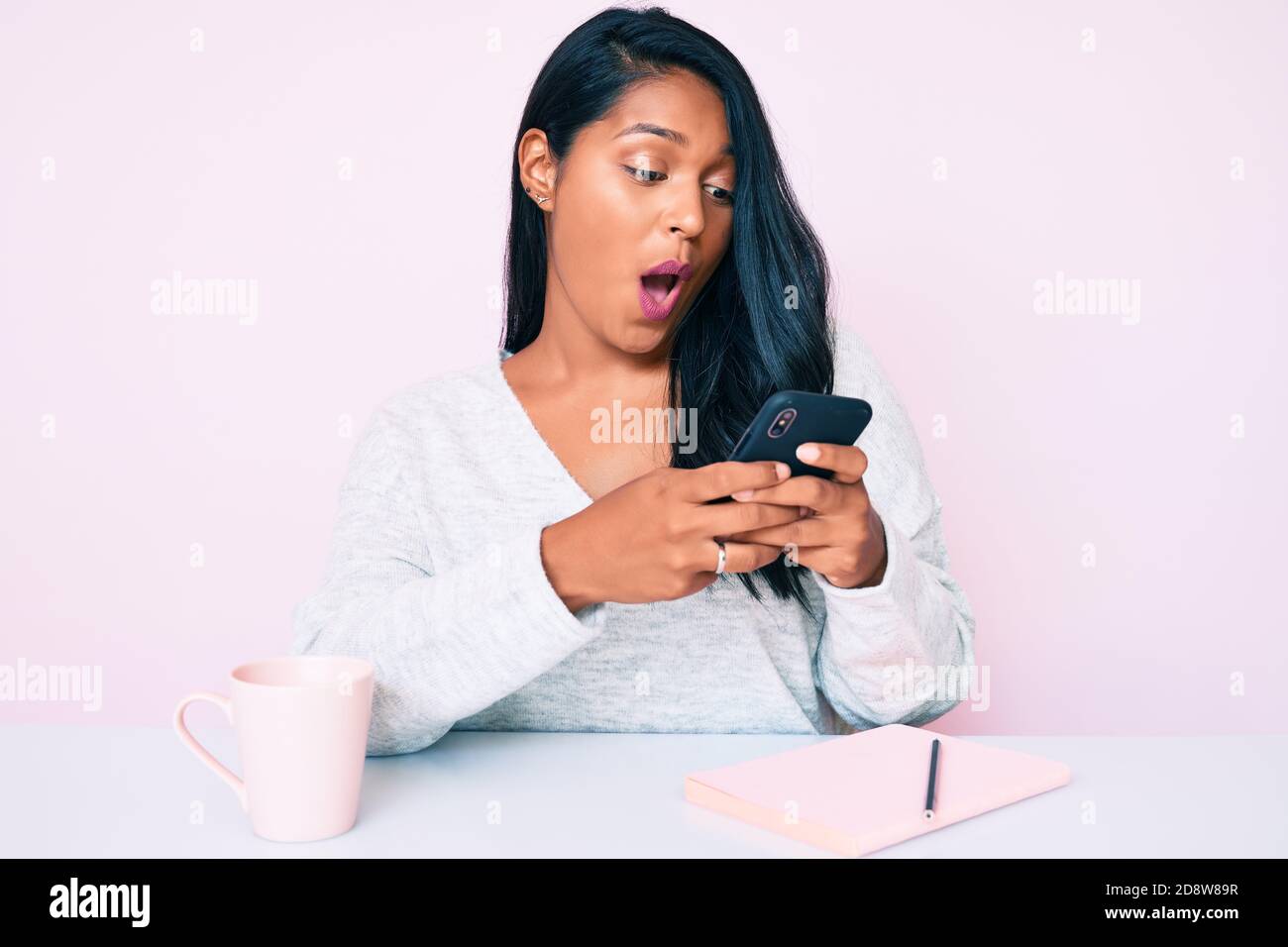 Beautiful latin young woman with long hair using smartphone sitting on ...