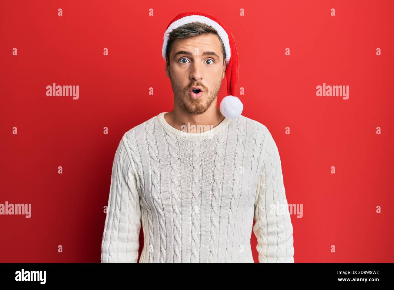 Handsome caucasian man wearing christmas hat scared and amazed with ...
