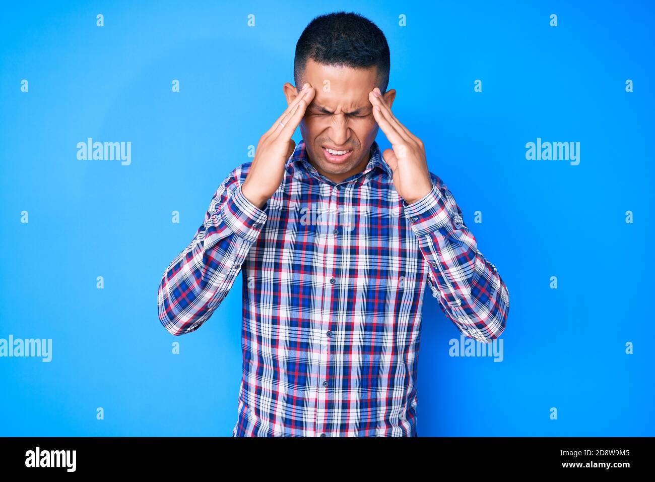 Young handsome latin man wearing casual clothes with hand on head for ...