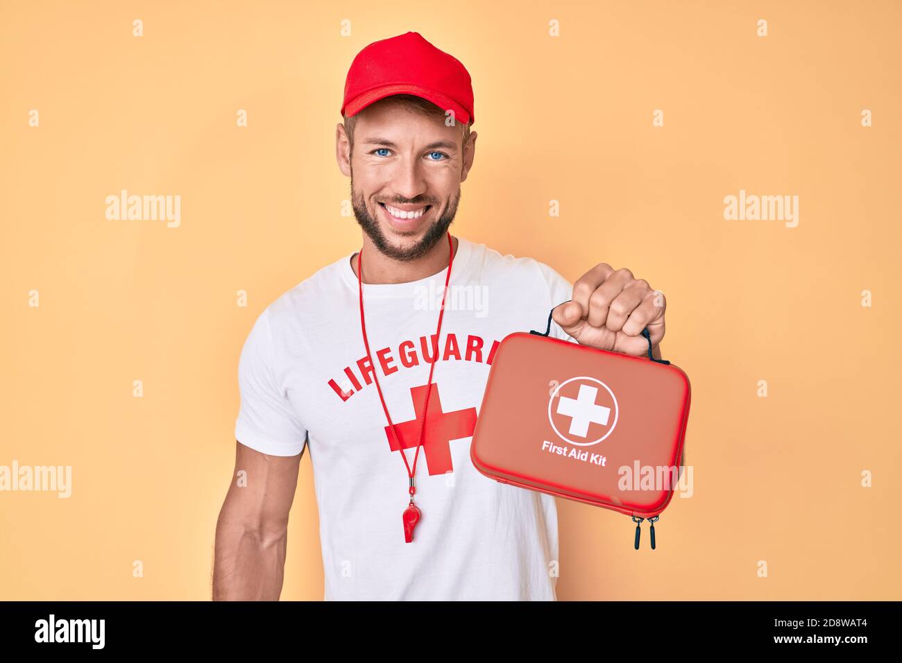 Young caucasian man wearing lifeguard t shirt holding first aid kit ...
