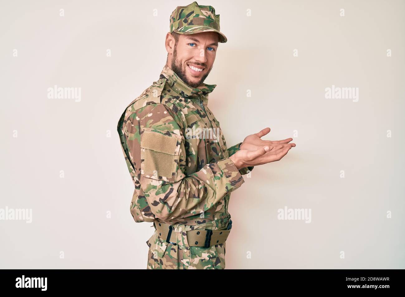 Young caucasian man wearing camouflage army uniform pointing aside with ...