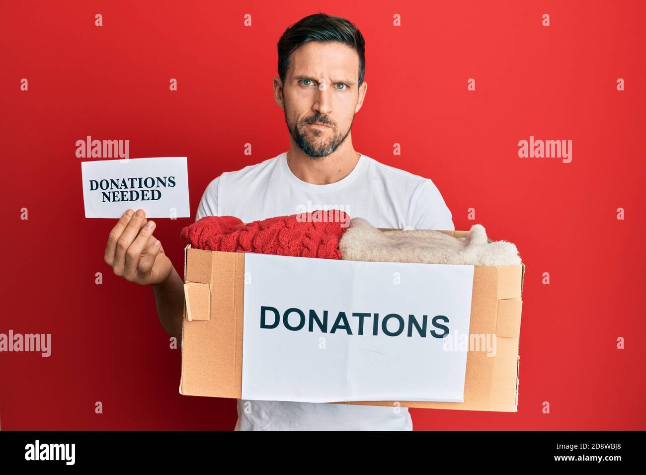 Young handsome man volunteer holding box and donations needed paper ...