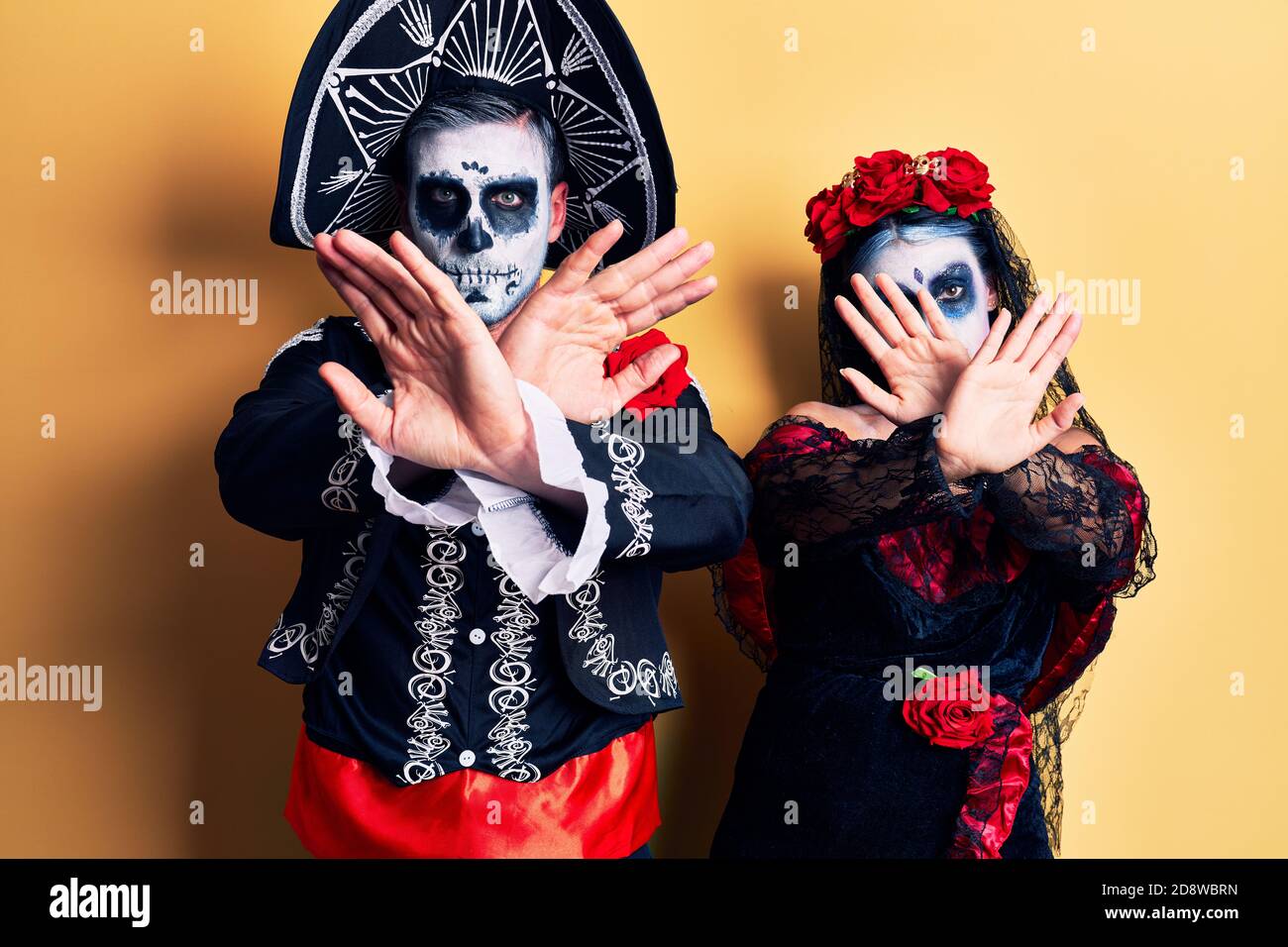 Young couple wearing mexican day of the dead costume over yellow ...