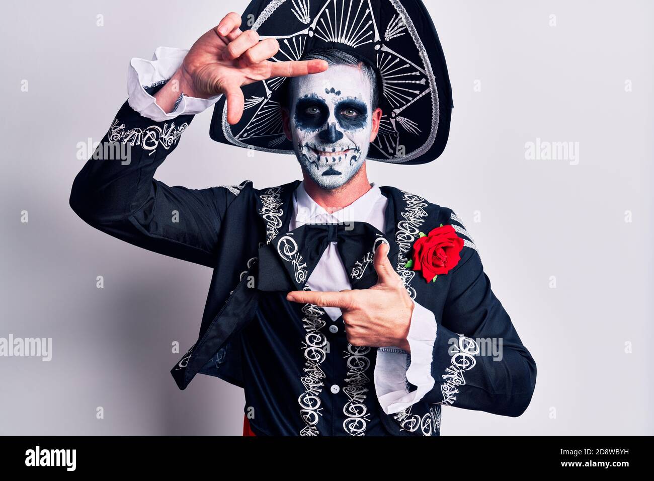 Young man wearing mexican day of the dead costume over white smiling ...