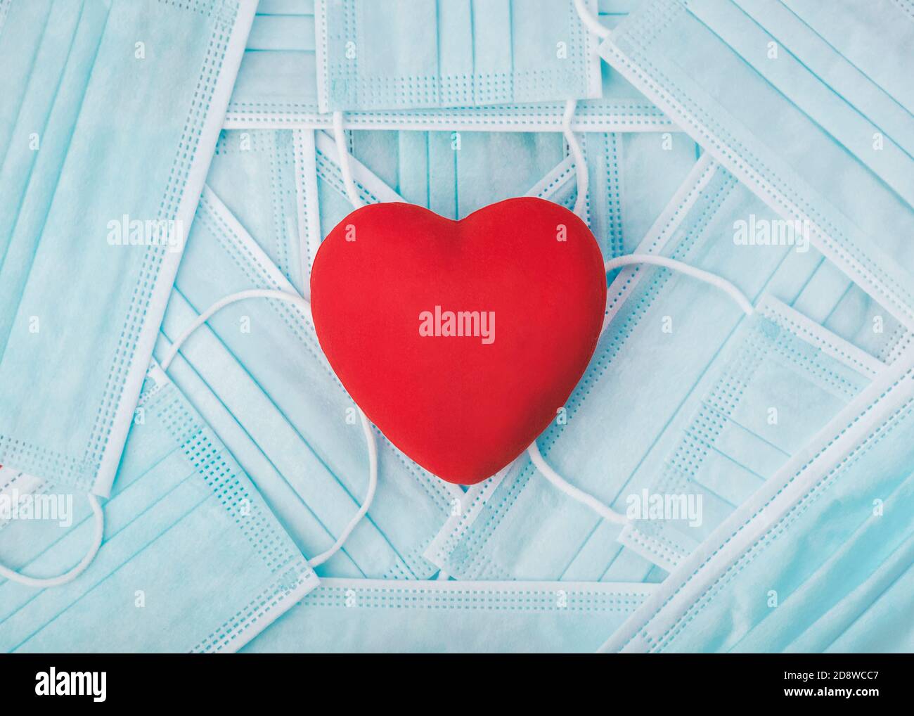 Red heart on a pile of medical face masks. Covid 19 concept. Healthcare ...