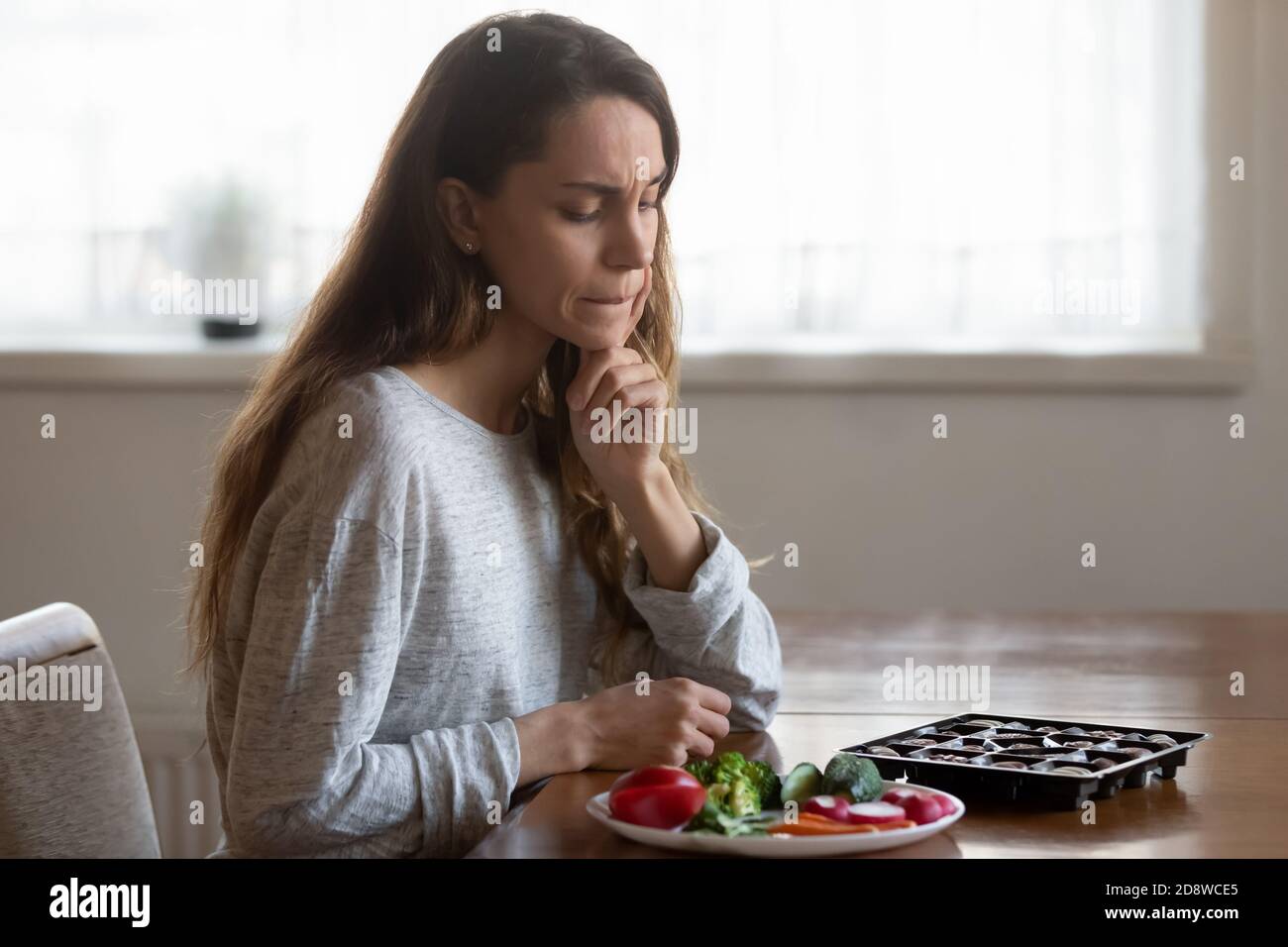 Confused young lady hesitating what to choose, salad or sweets Stock ...