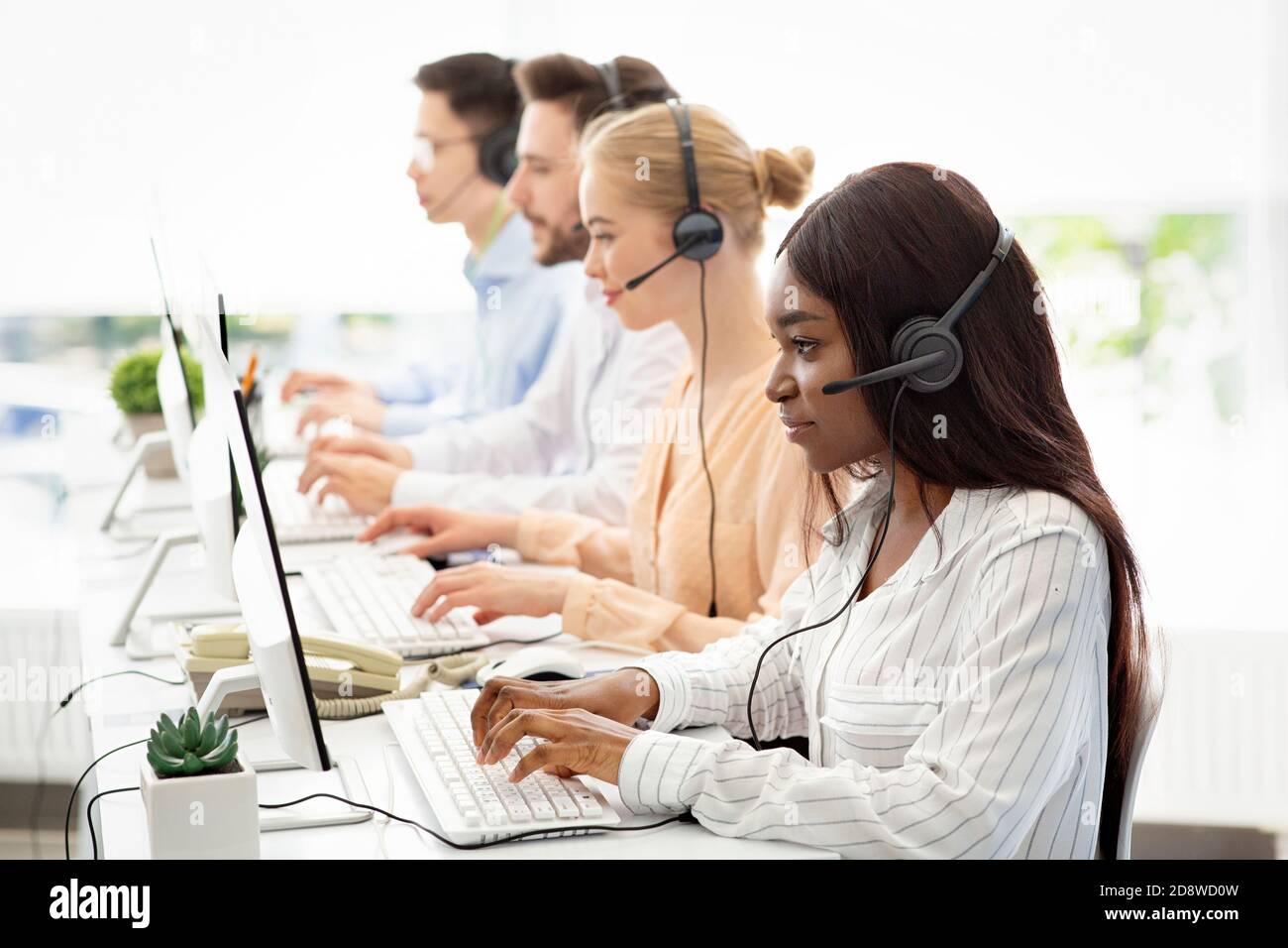 Focused call centre operators with headphones working with computers at ...