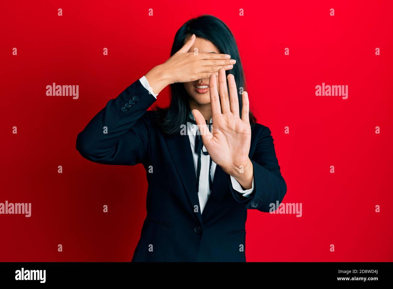 Beautiful asian young woman wearing business suit covering eyes with ...