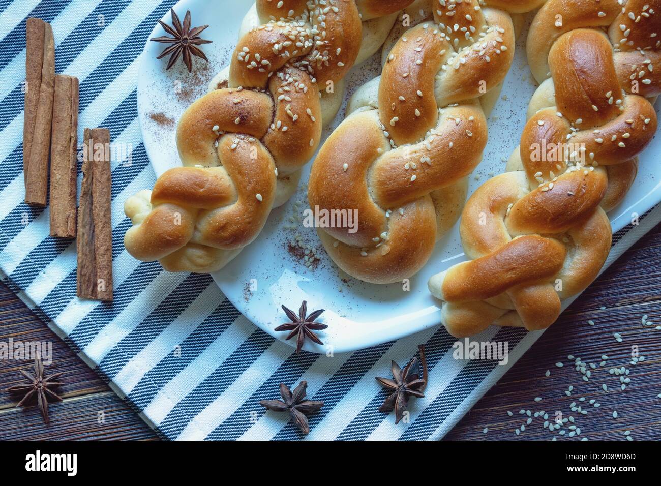 Homemade braided pastries with cinnamon and sesame seeds on rustic ...