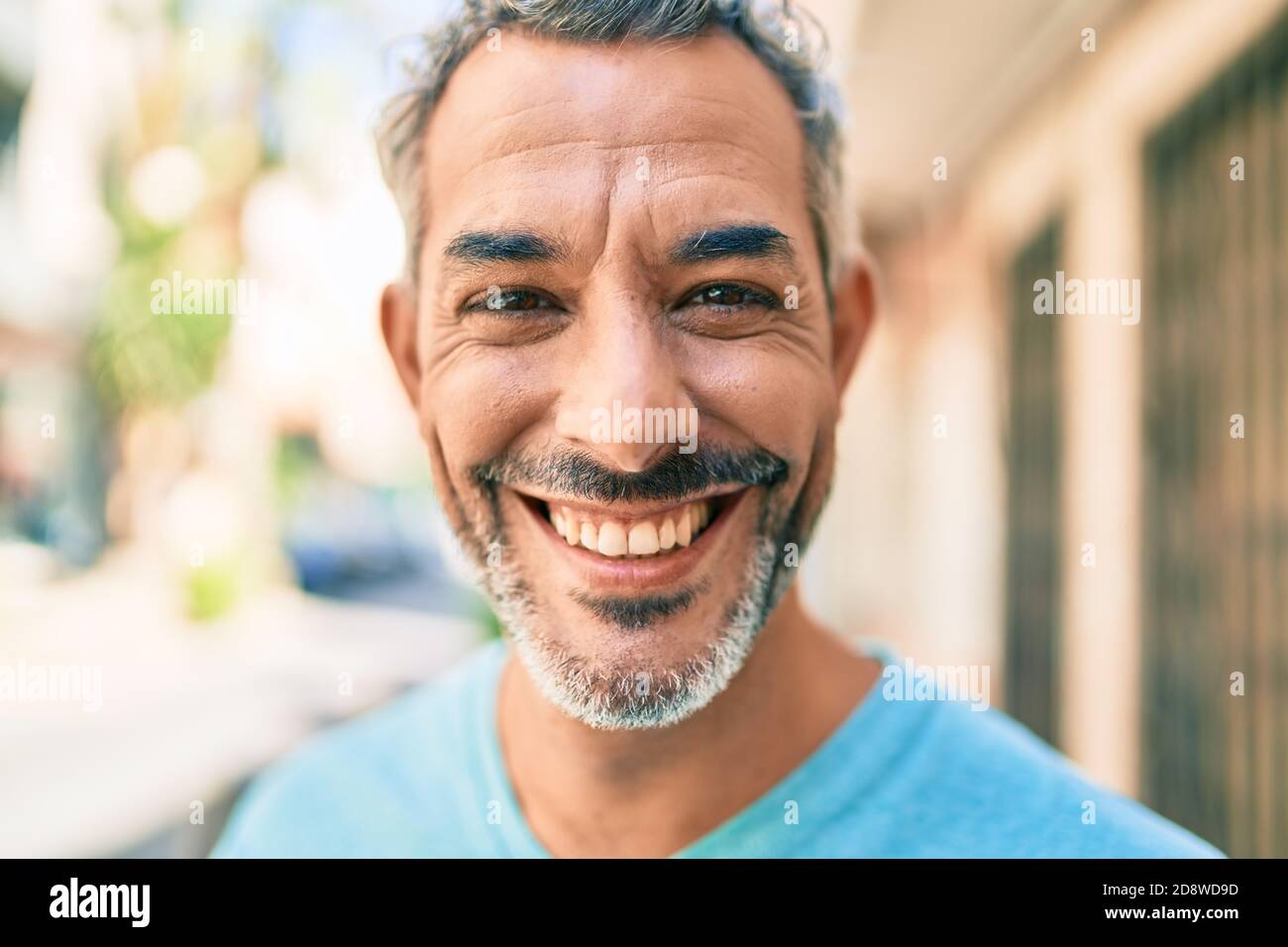 Middle age grey-haired man smiling happy walking at street of city ...