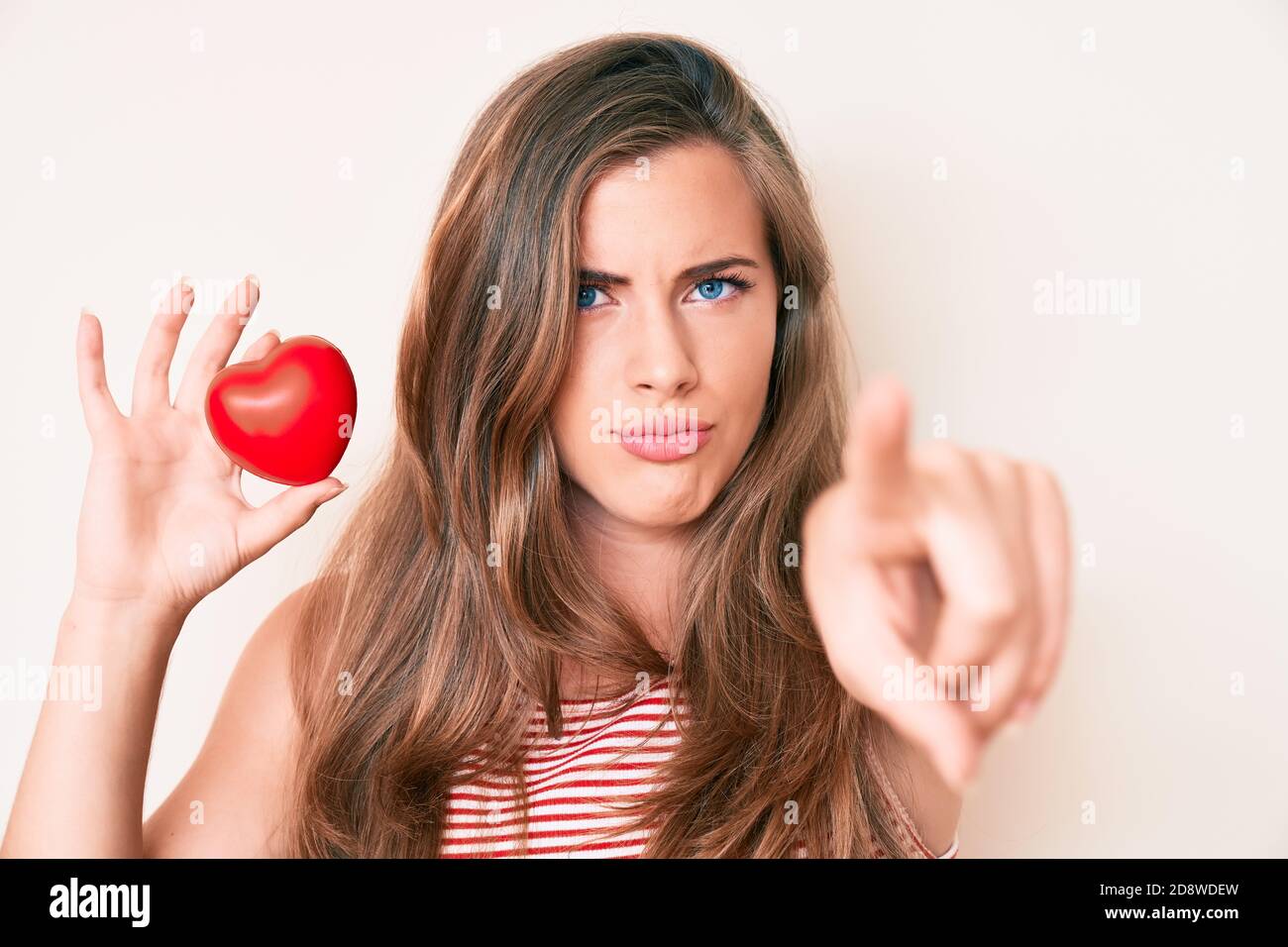 Beautiful young caucasian woman holding heart pointing with finger to ...