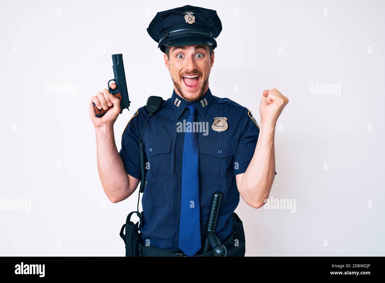 Young caucasian man wearing police uniform holding gun screaming proud ...