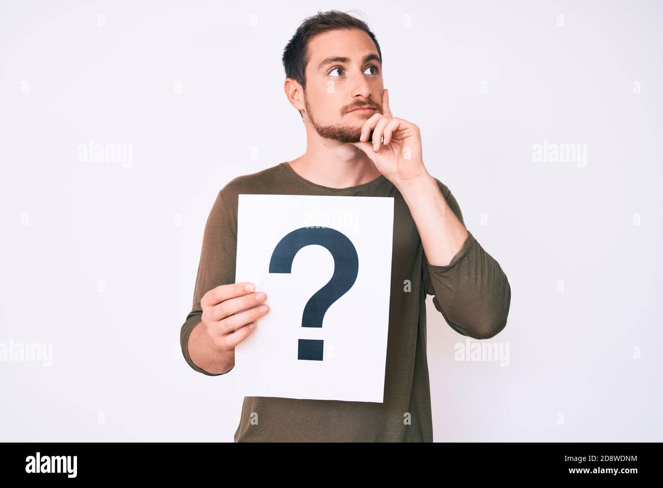 Young handsome man holding question mark serious face thinking about ...