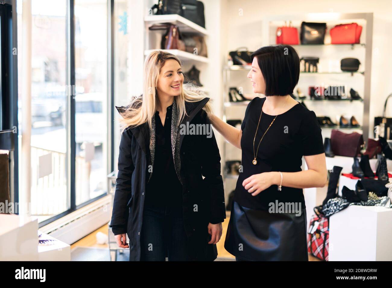 A seller propose to try boot to a female client Stock Photo - Alamy