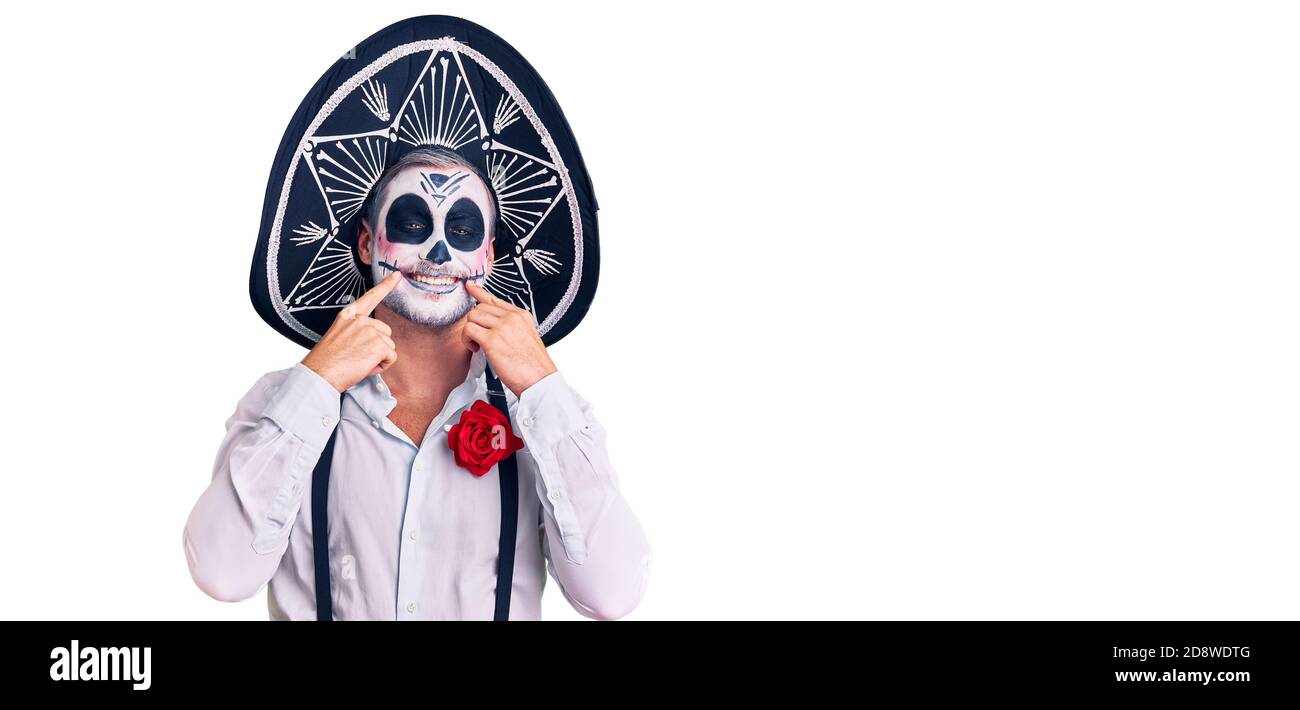Man wearing day of the dead costume over background smiling with open ...