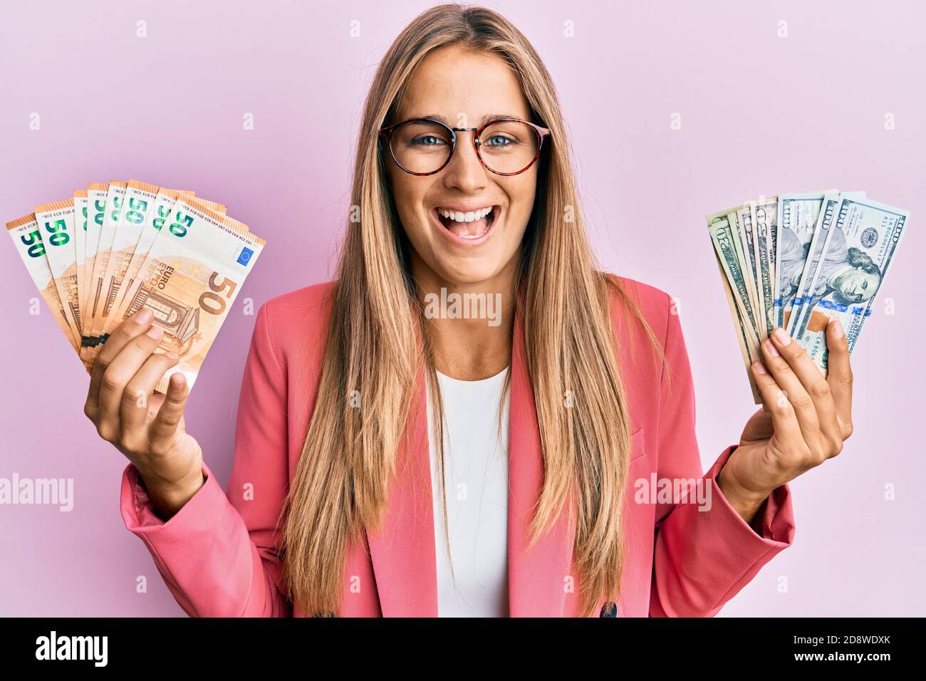 Young blonde woman wearing business style holding dollars and euros ...