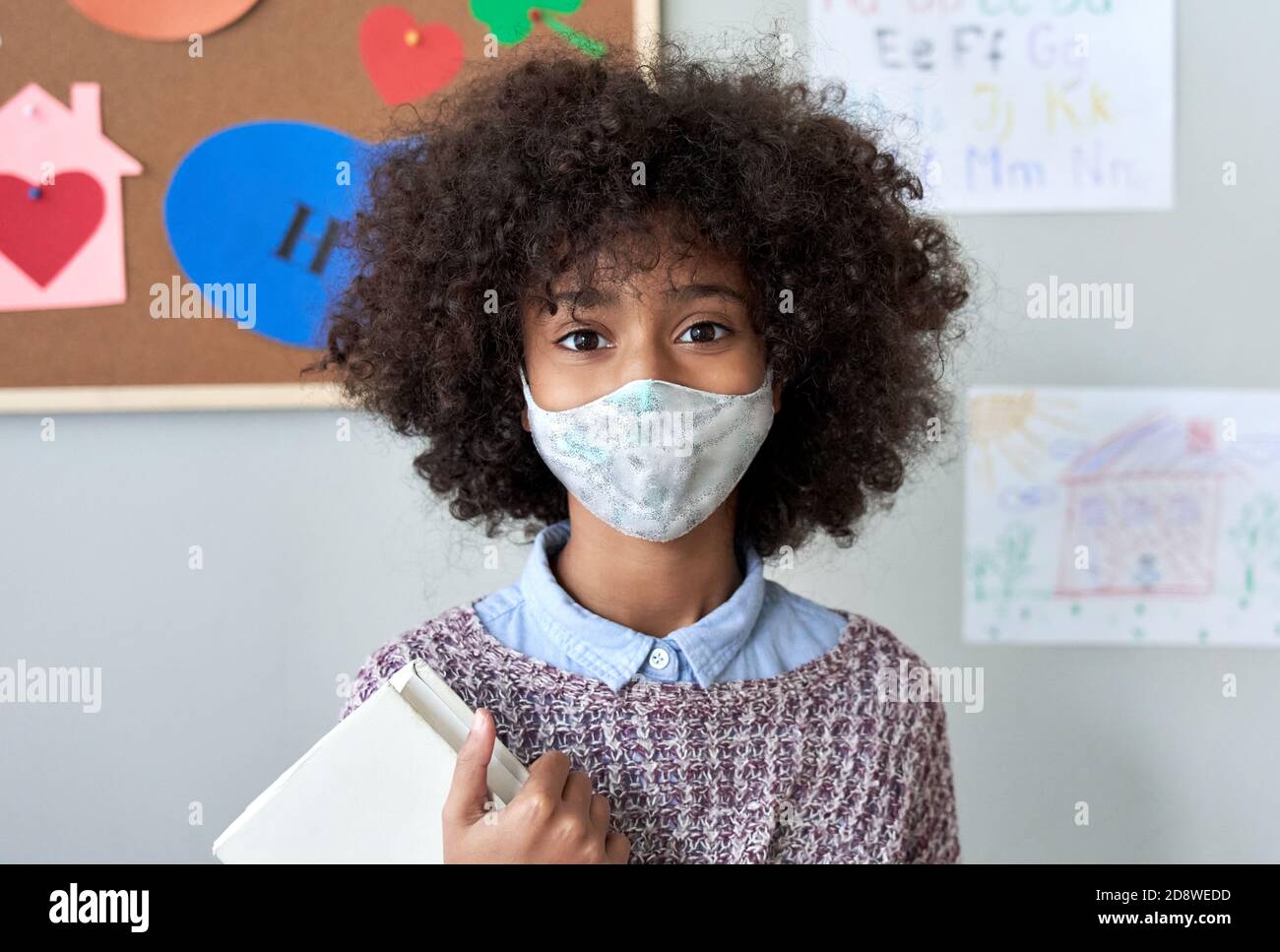 African school child girl wearing face mask in classroom, headshot ...