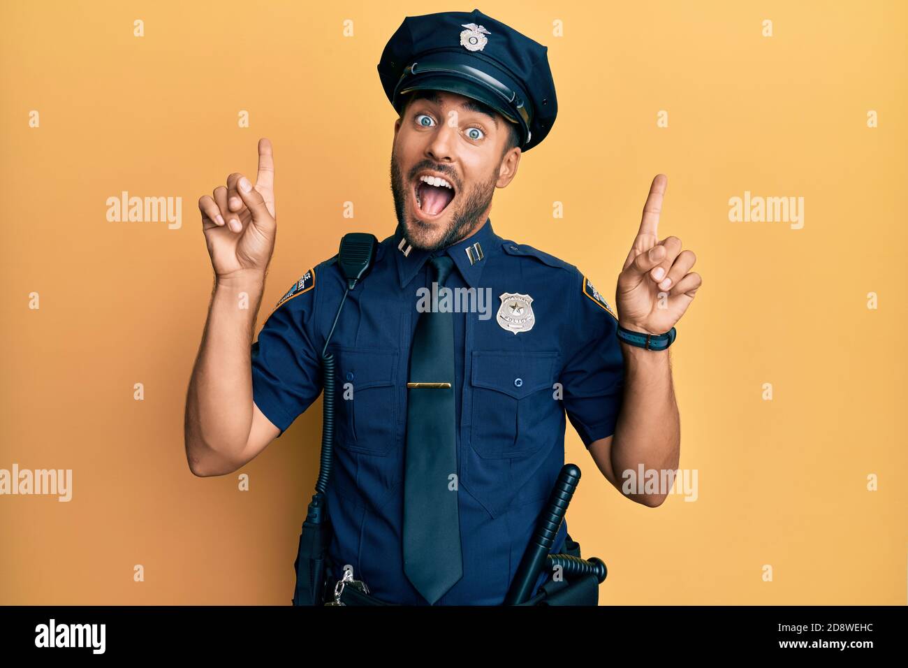 Handsome hispanic man wearing police uniform smiling amazed and ...