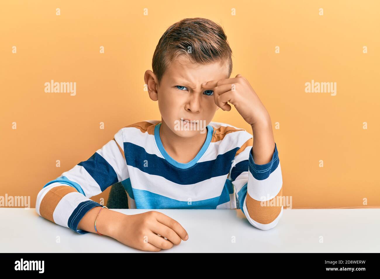 Adorable caucasian kid wearing casual clothes sitting on the table ...