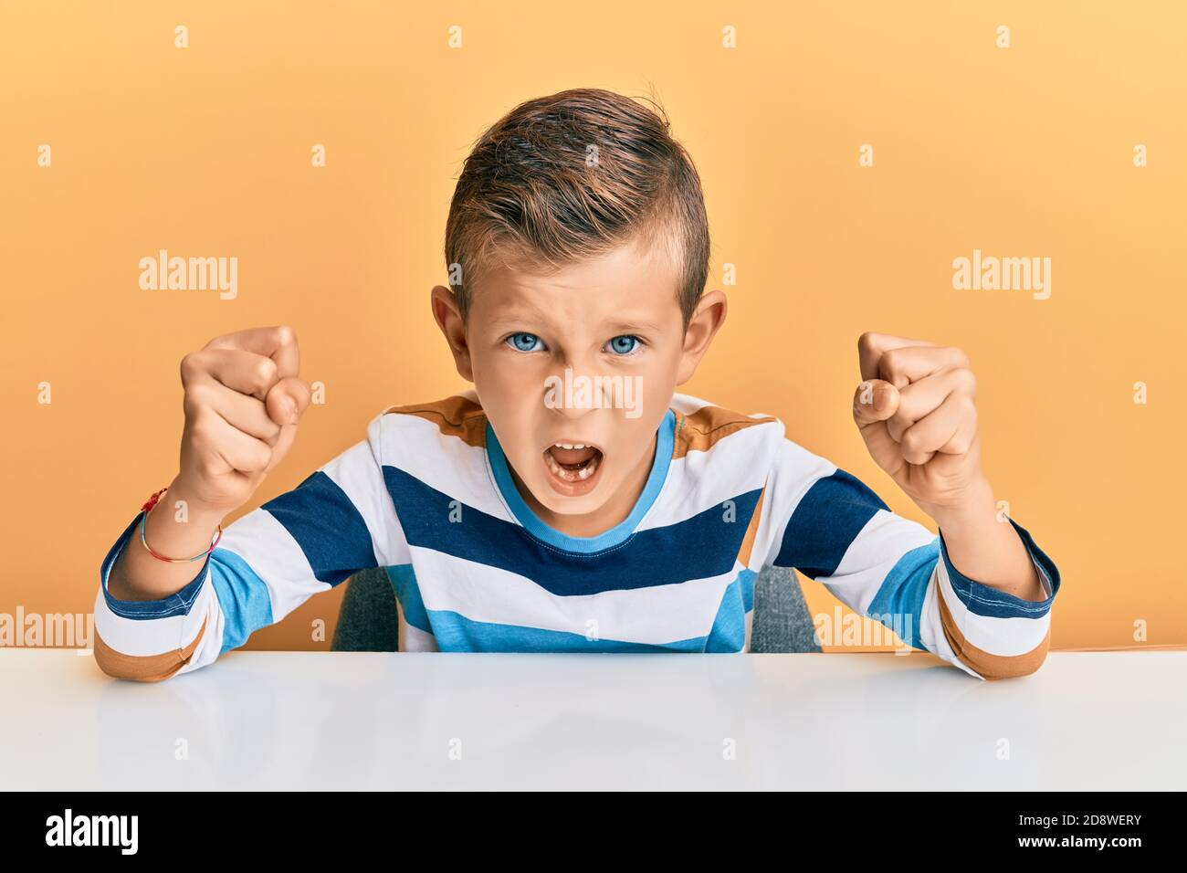 Adorable caucasian kid wearing casual clothes sitting on the table ...
