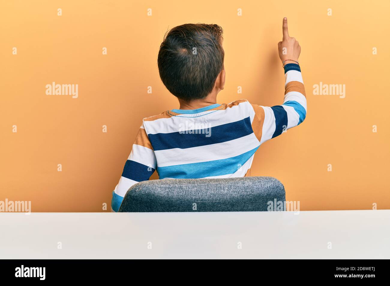 Adorable caucasian kid wearing casual clothes sitting on the table ...