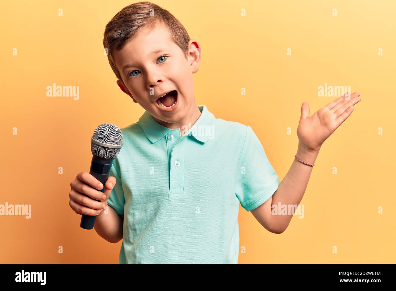 Cute blond kid singing song using microphone celebrating achievement ...