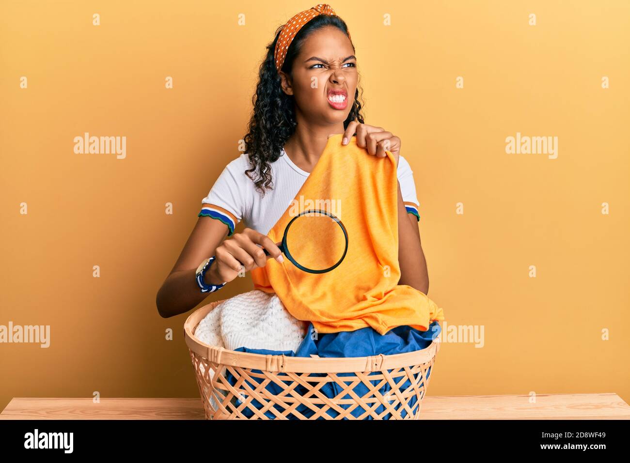 Young african american girl holding magnifying glass looking for stain ...