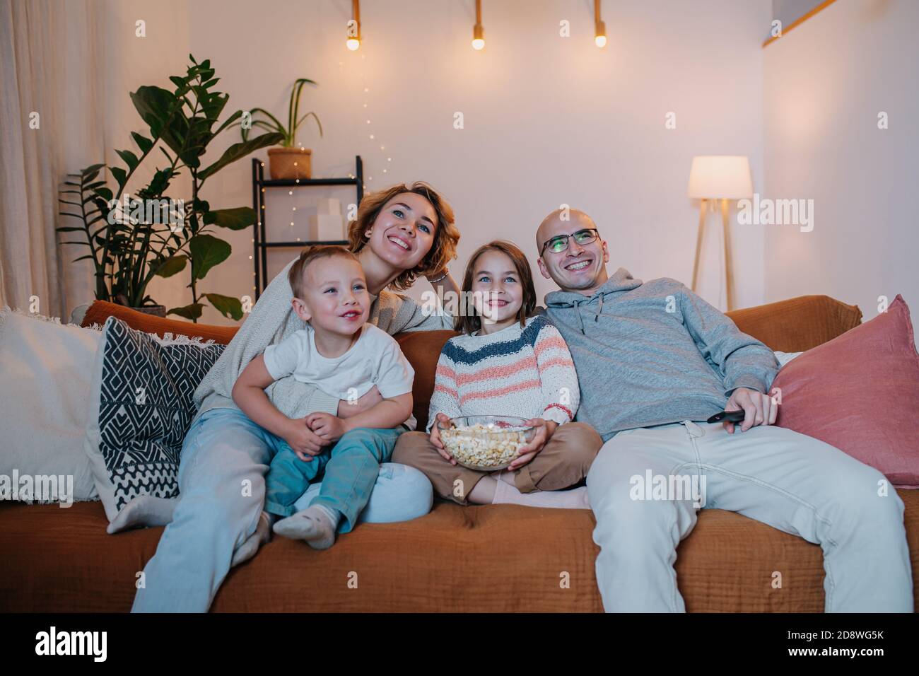 Happy family watching television together on the couch in the living ...