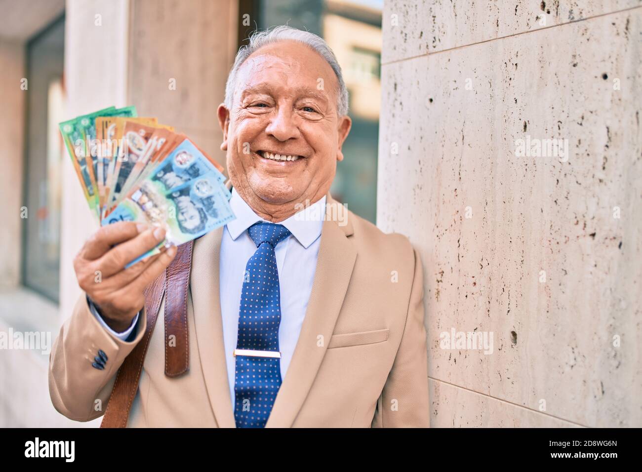 Senior grey-haired businessman smiling happy holding australian dollars ...