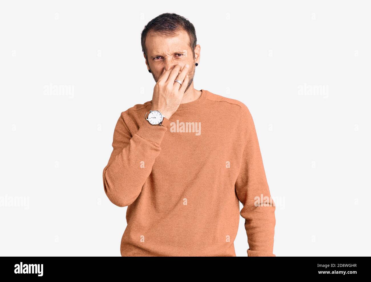 Young handsome man wearing casual clothes smelling something stinky and ...