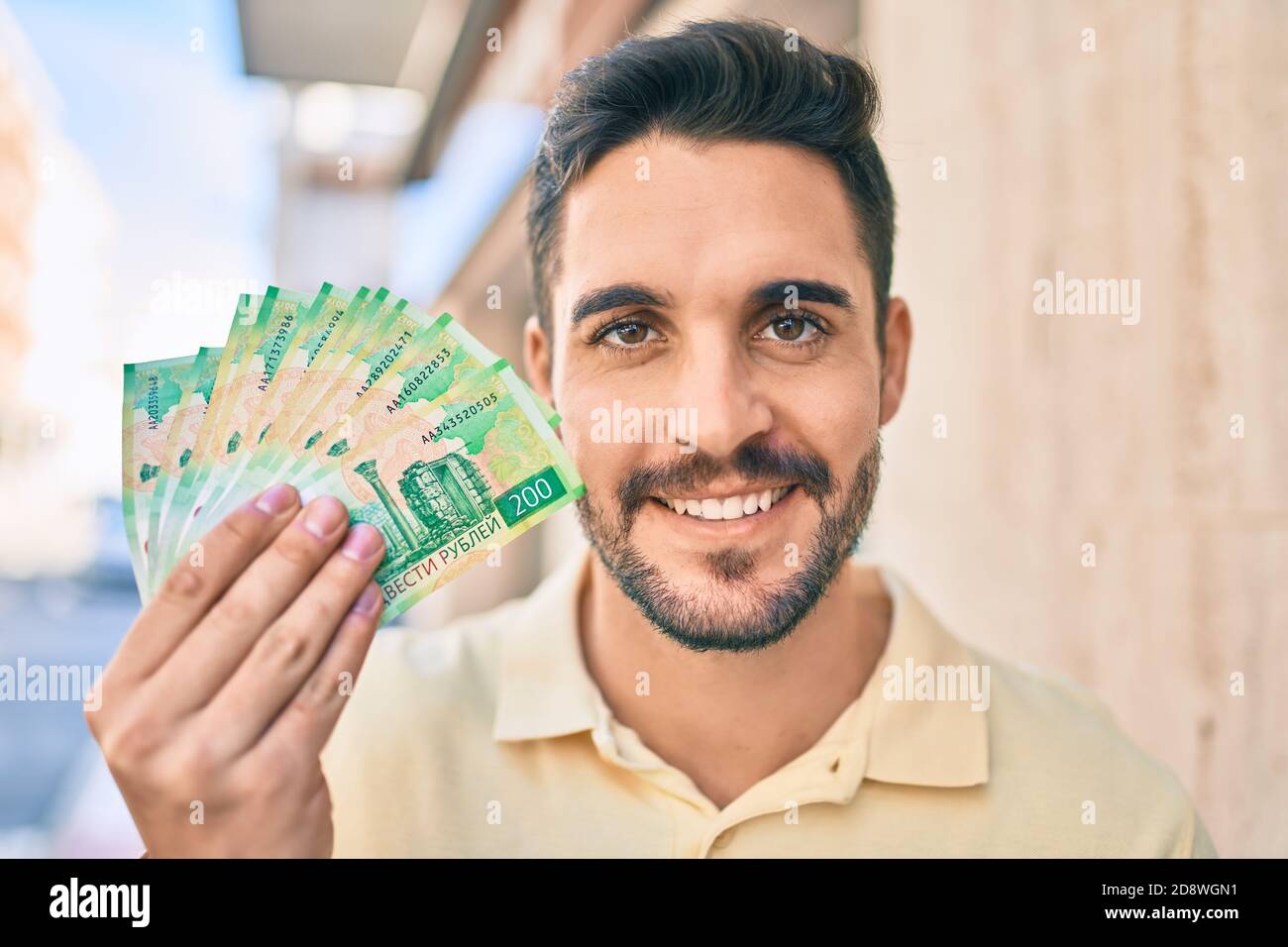 Young hispanic man smiling happy holding russian rubles banknotes ...