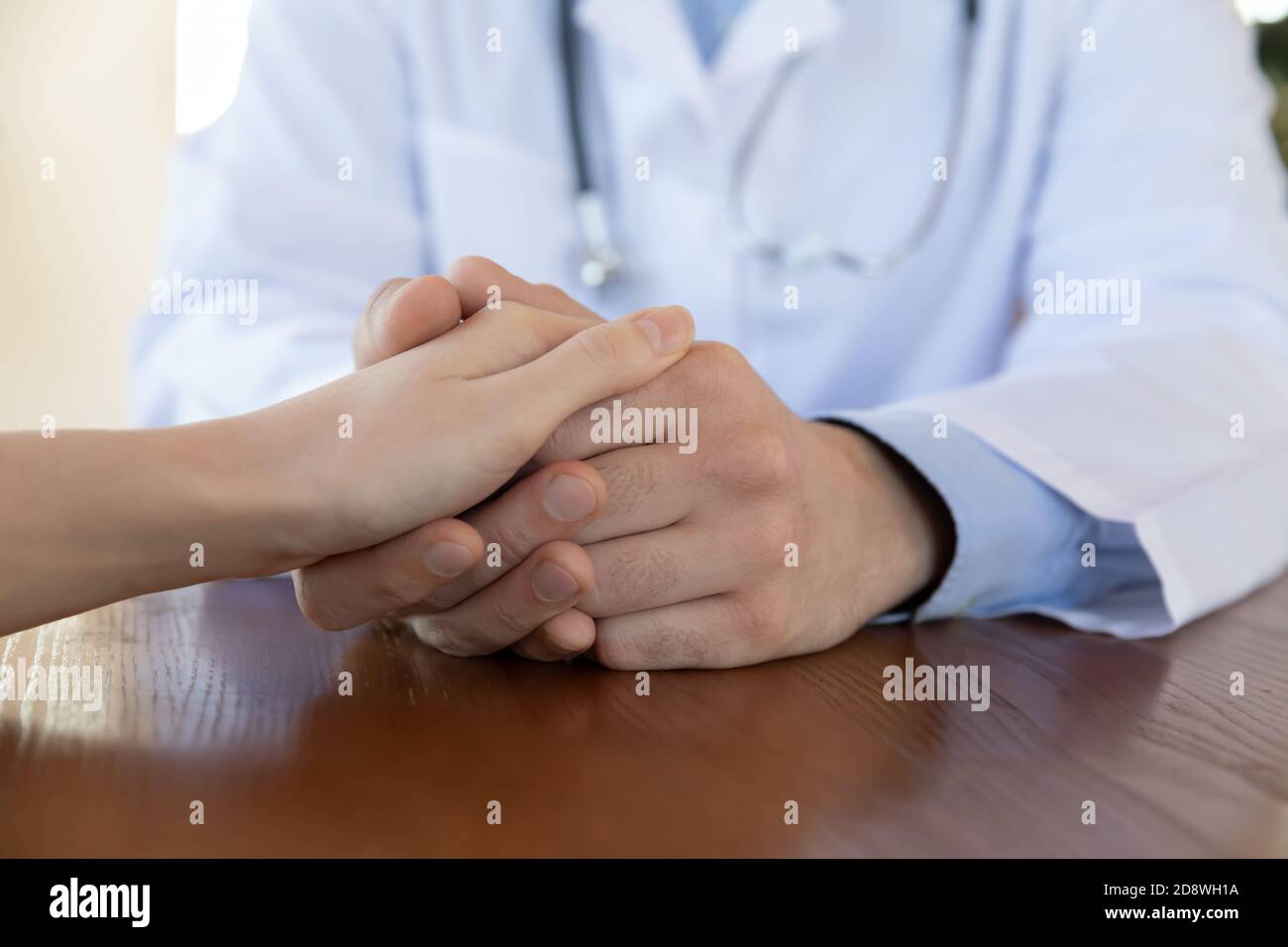Caring male doctor talking with female patient holding her hand Stock ...