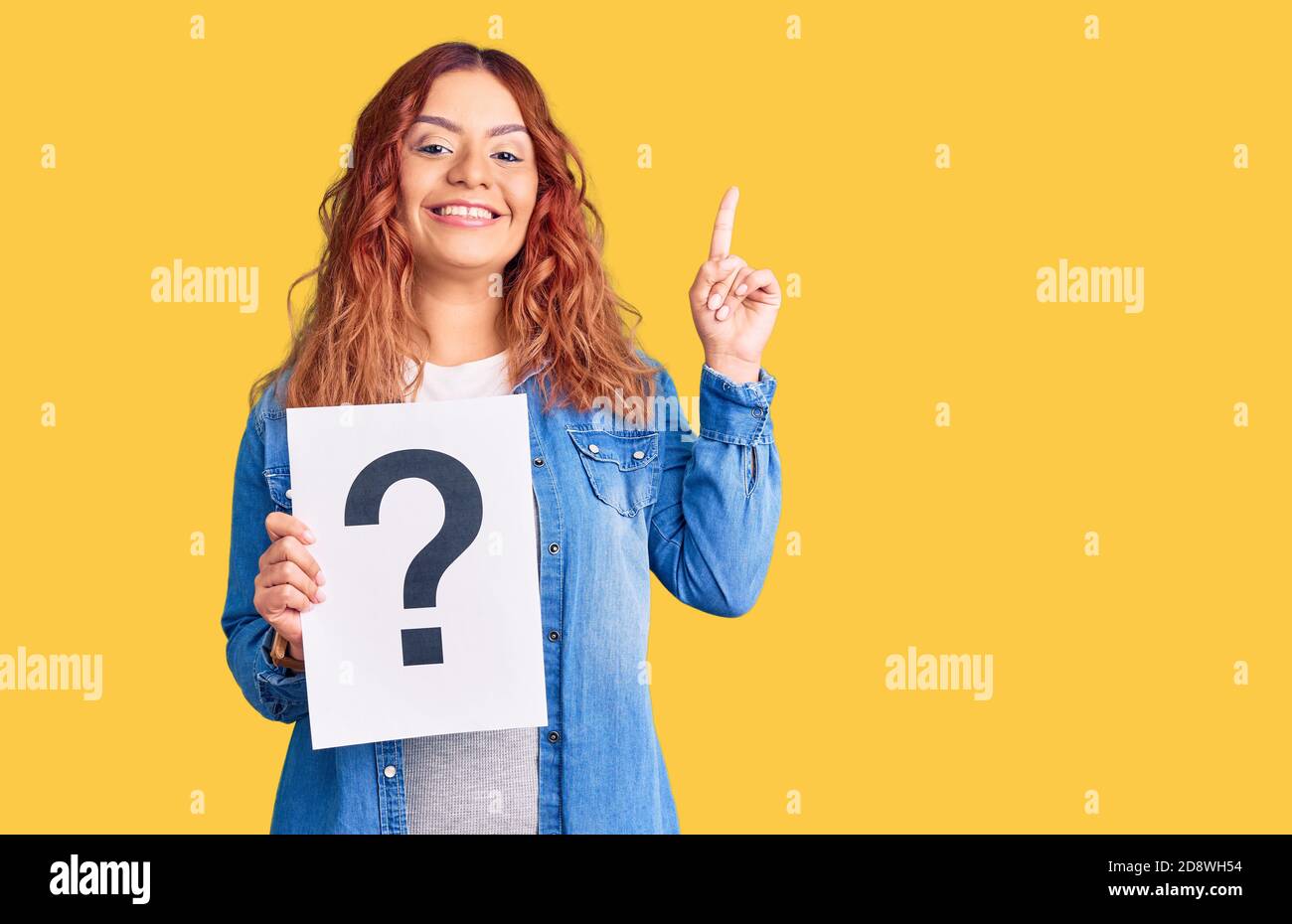 Young latin woman holding question mark surprised with an idea or ...