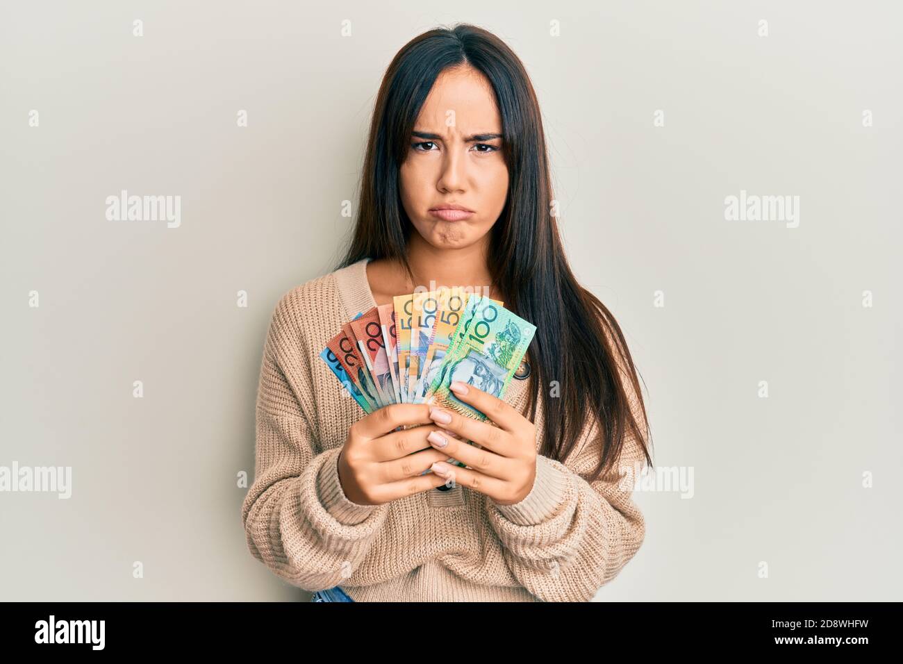 Young beautiful hispanic girl holding australian dollars depressed and ...