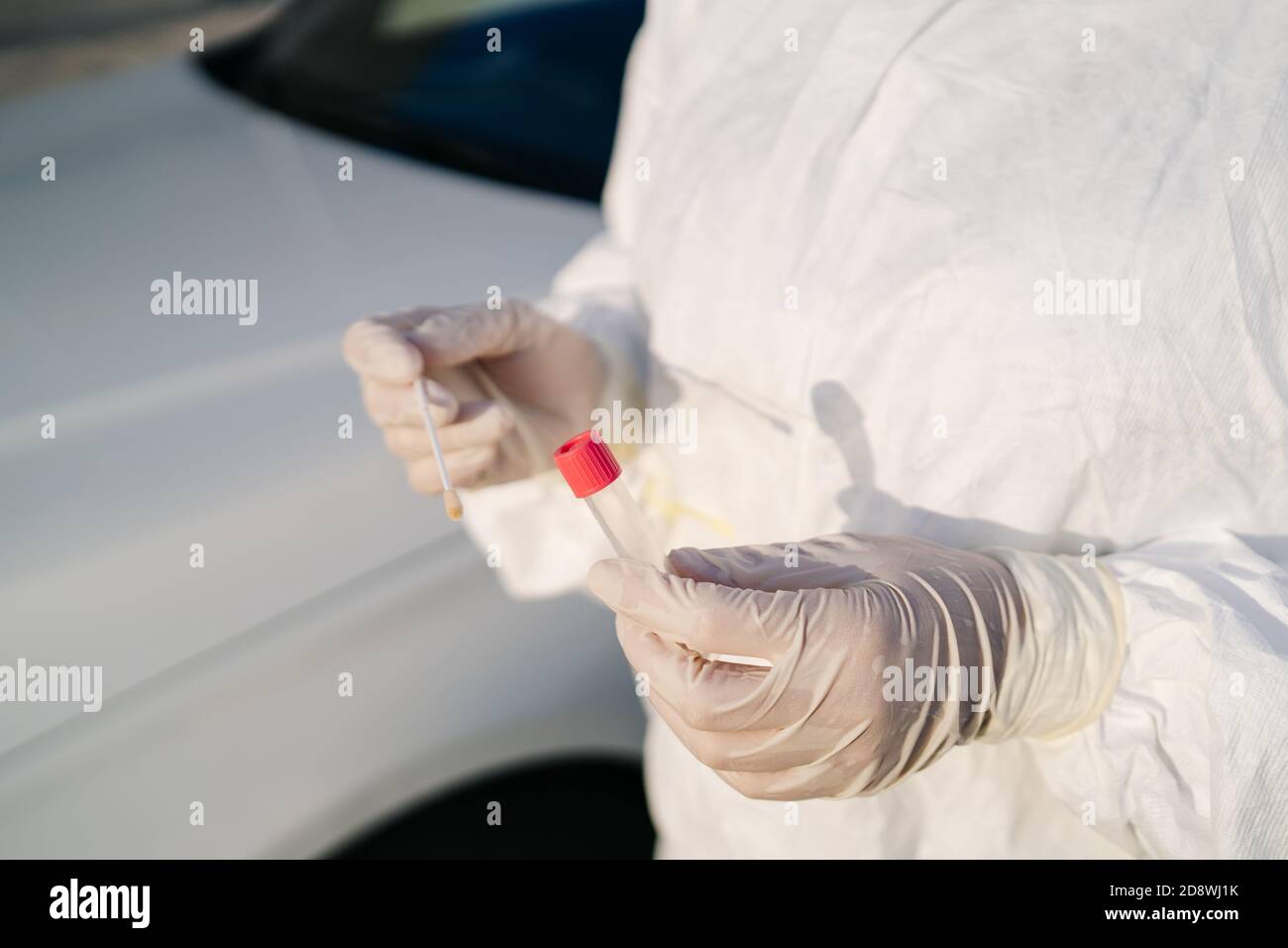 Doctor doing a PCR test COVID-19 on a patient through the car window ...