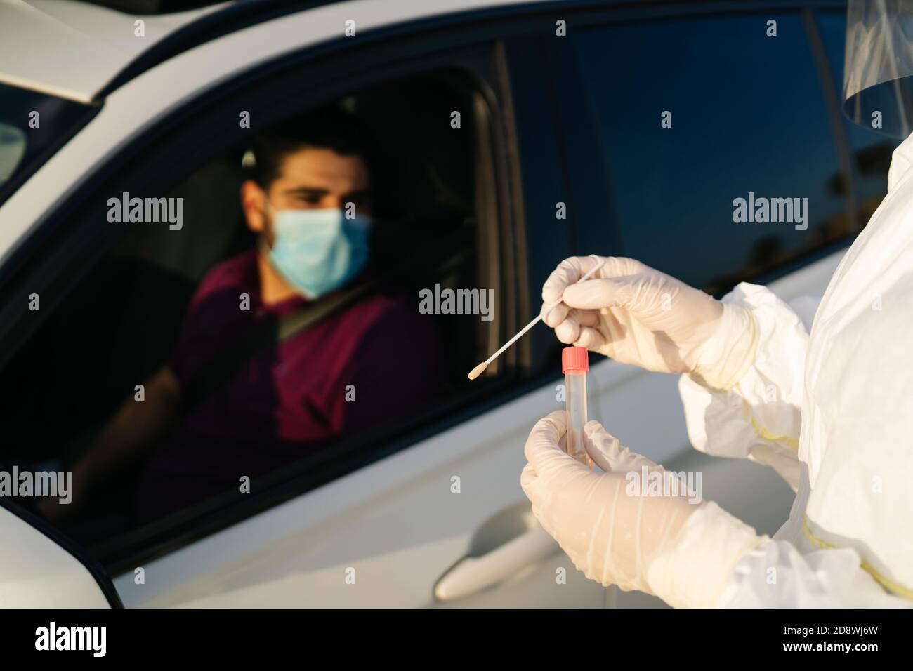 Doctor doing a PCR test COVID-19 on a patient through the car window ...
