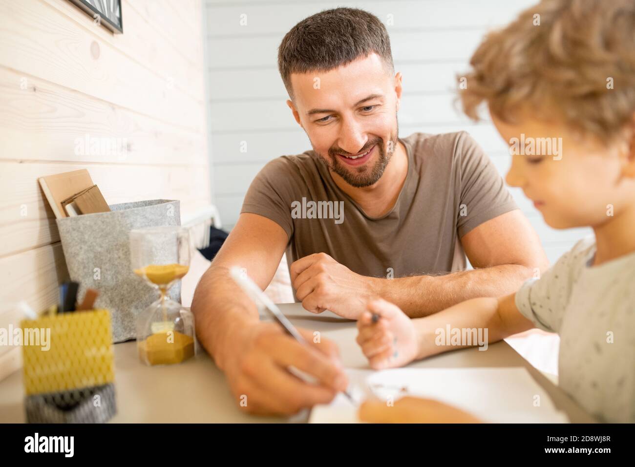 Young happy father with crayon helping his cute little son with drawing ...