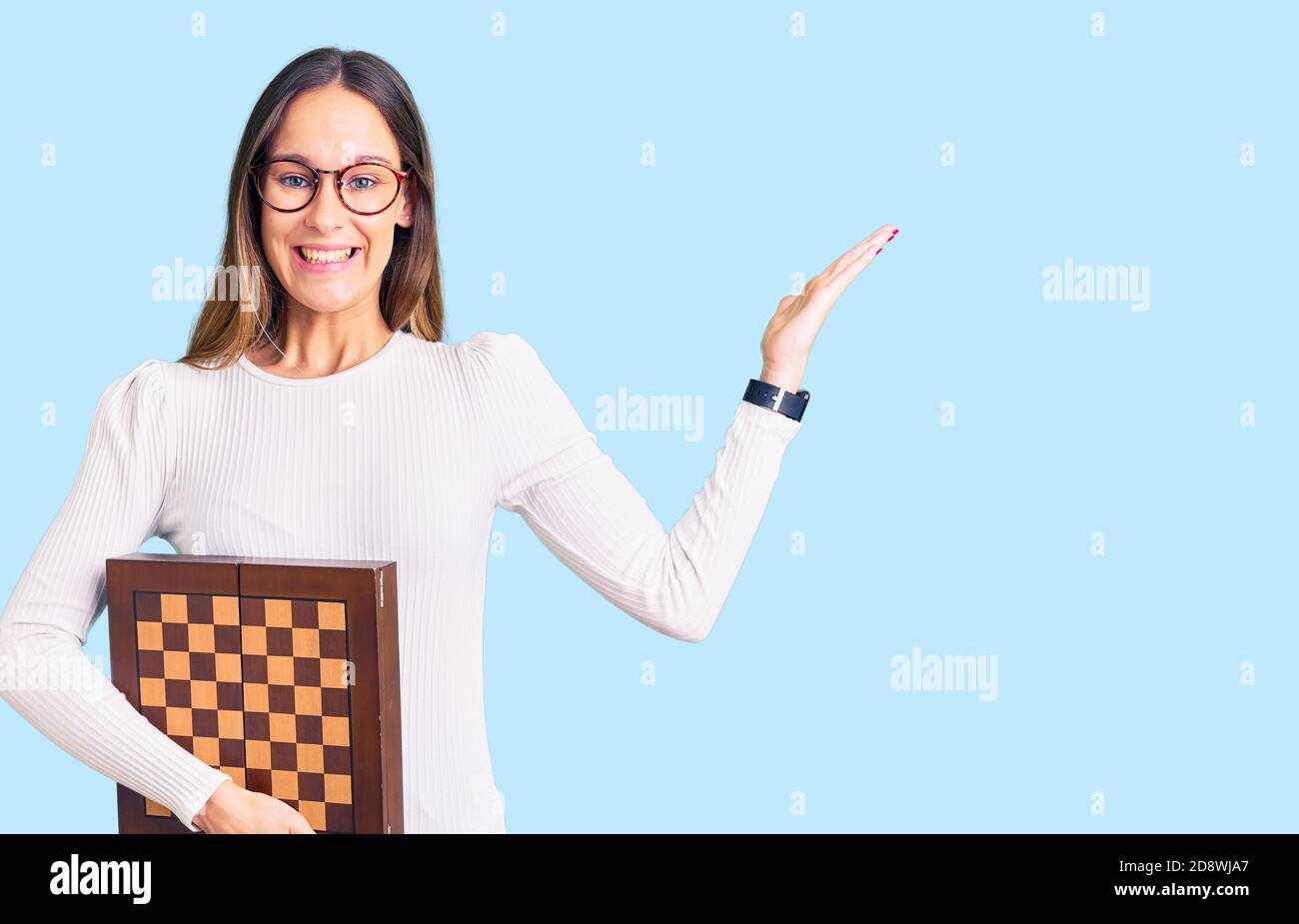 Beautiful brunette young woman holding chess celebrating victory with ...