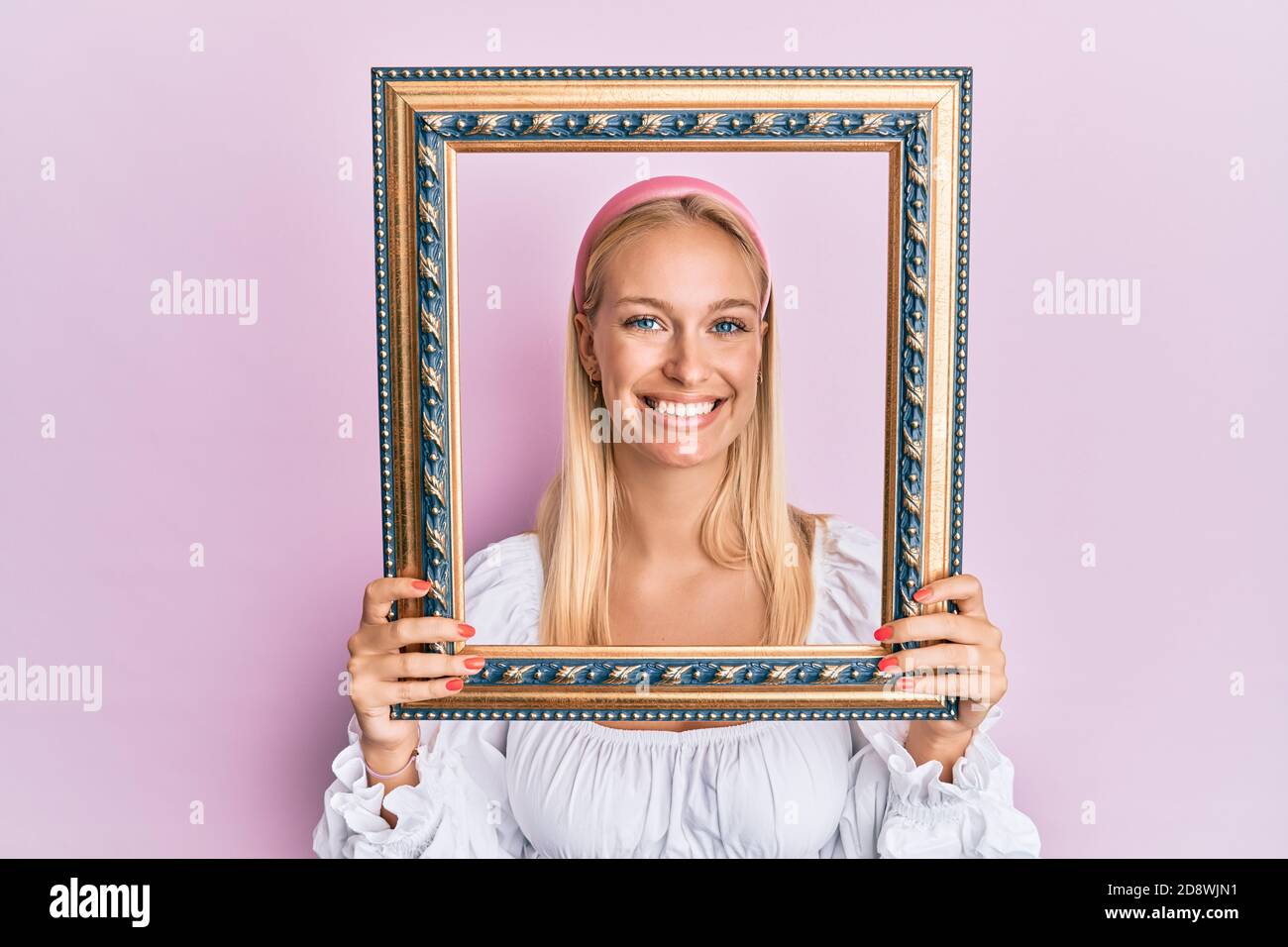 Young blonde girl holding empty frame smiling with a happy and cool ...