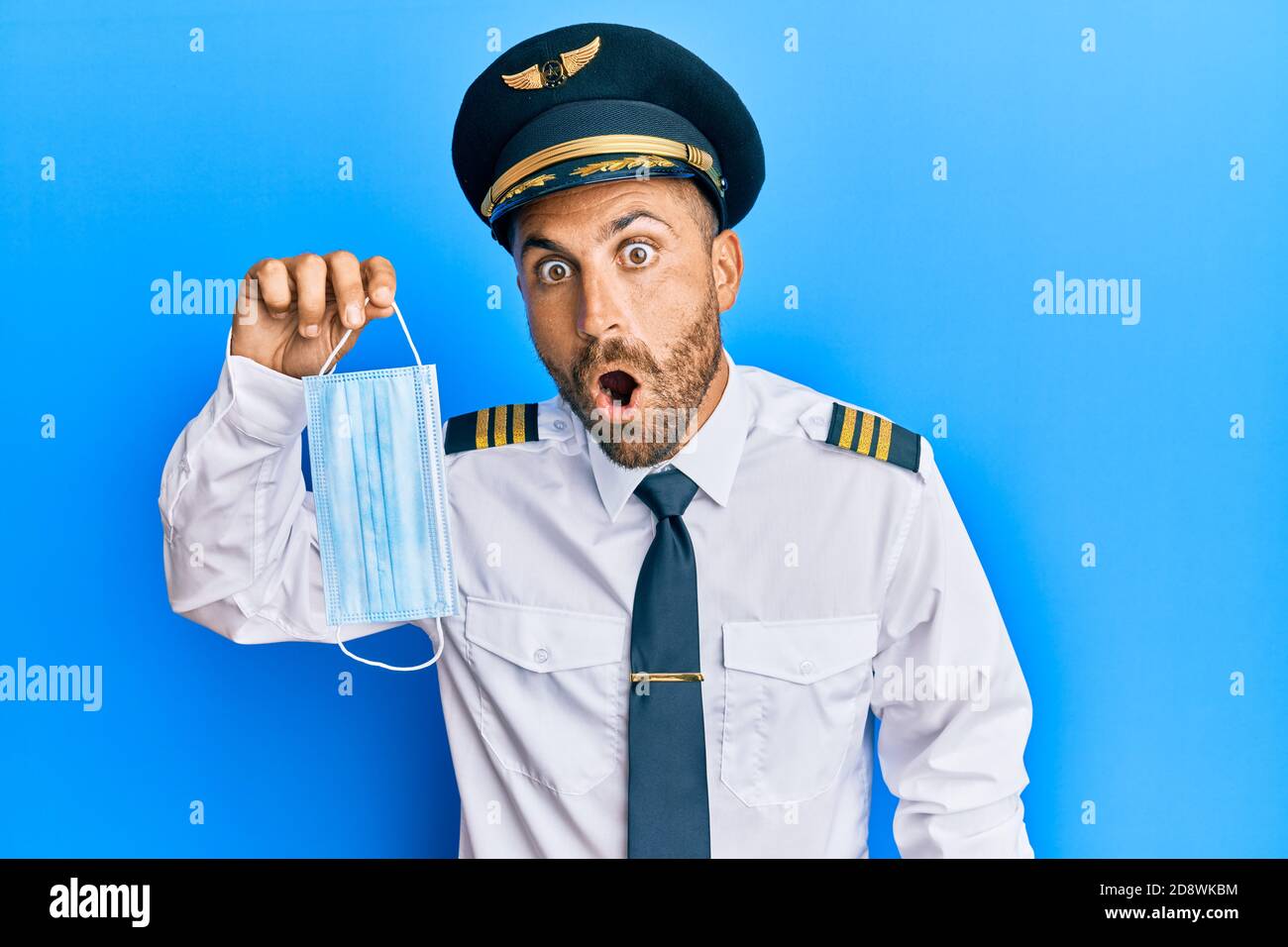 Handsome man with beard wearing airplane pilot uniform holding safety ...