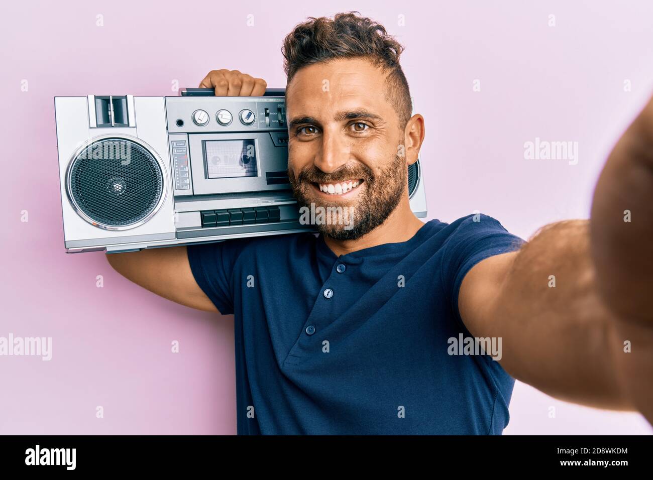 Handsome man with beard holding boombox, listening to music smiling ...