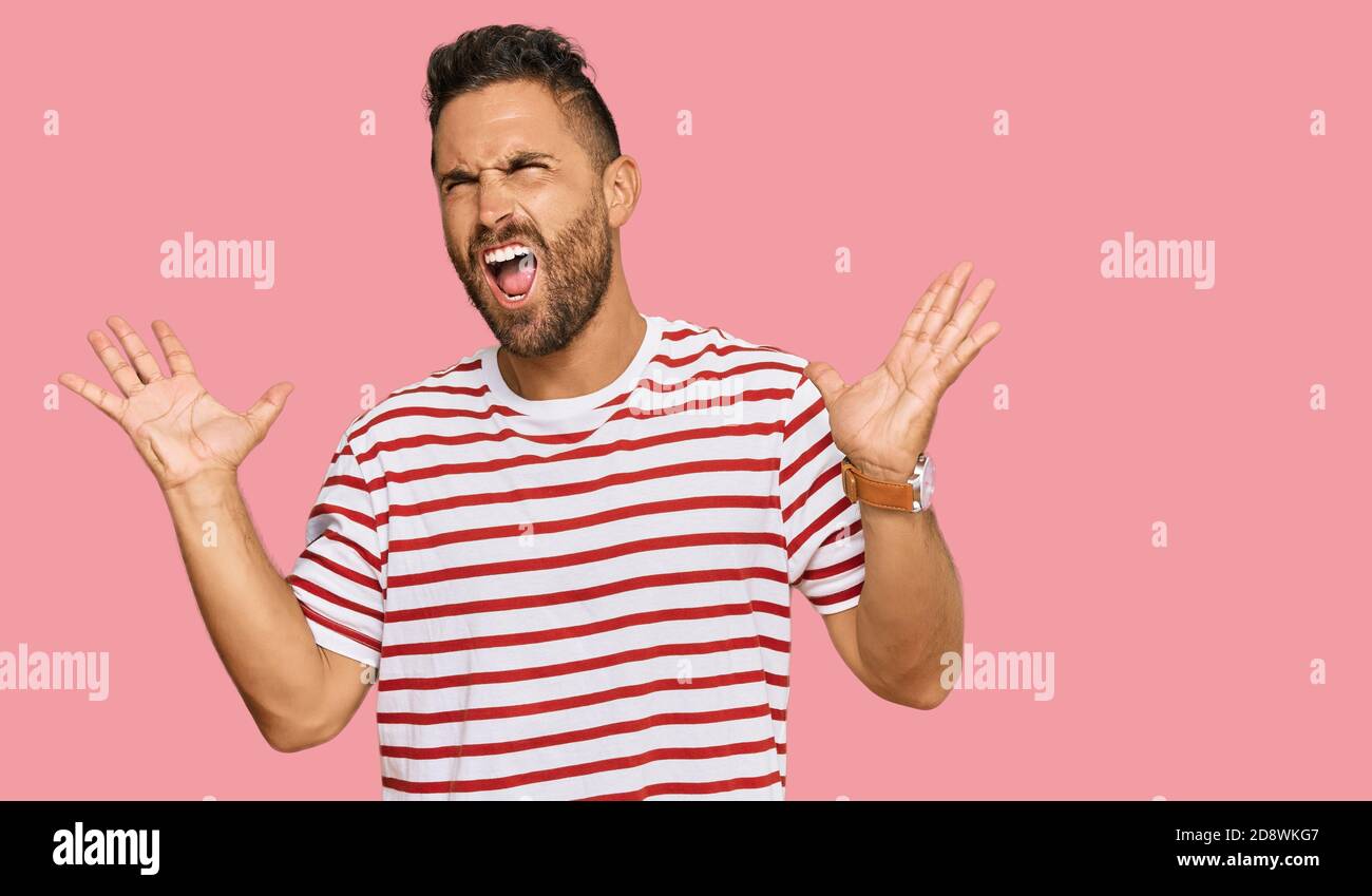 Handsome man with beard wearing striped tshirt celebrating mad and ...