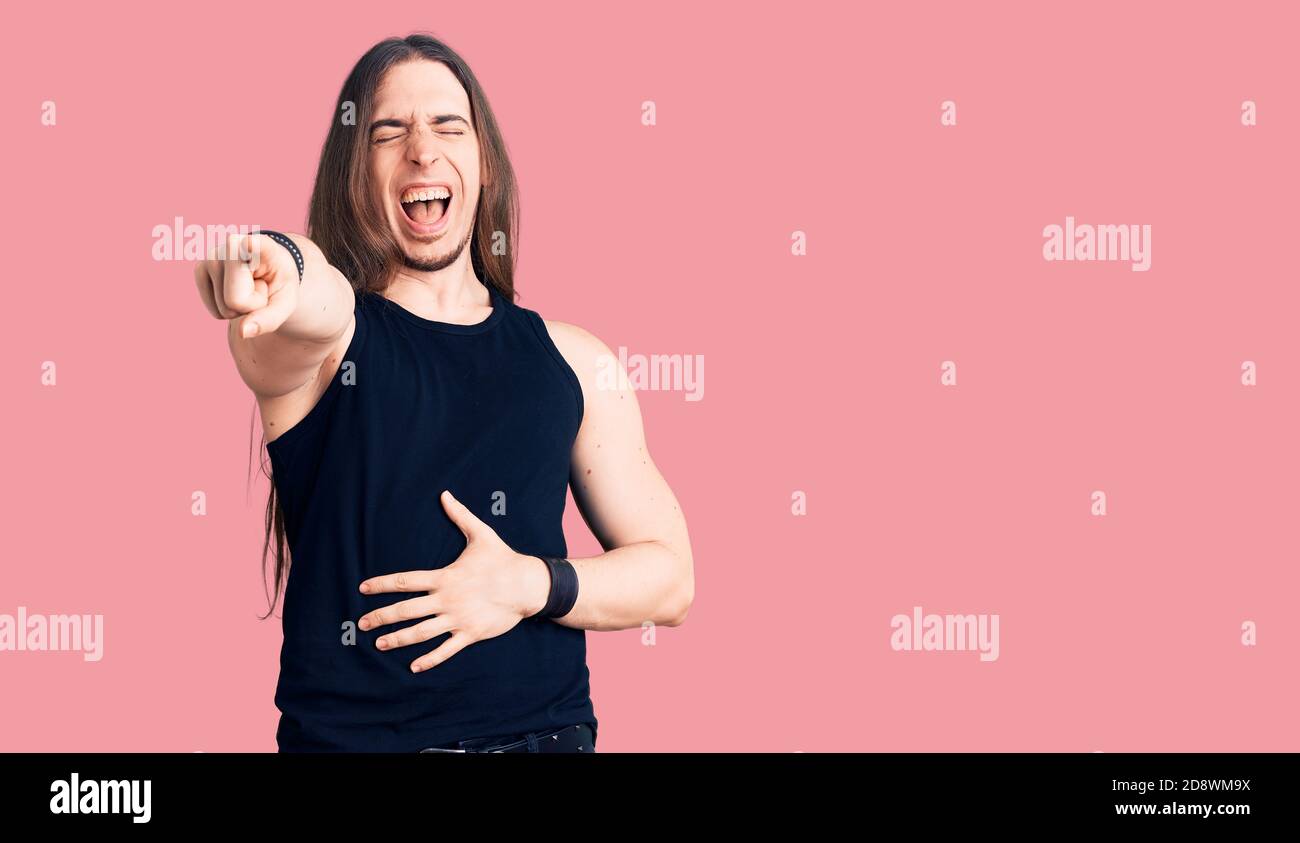 Young adult man with long hair wearing goth style with black clothes ...