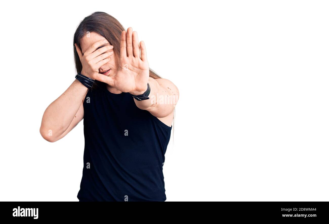 Young adult man with long hair wearing goth style with black clothes ...