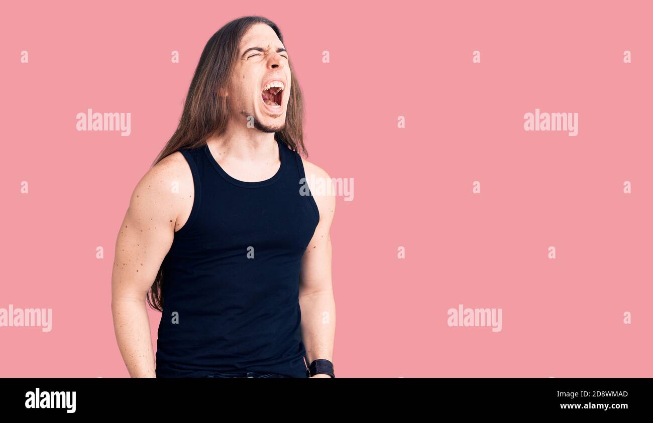 Young adult man with long hair wearing goth style with black clothes ...