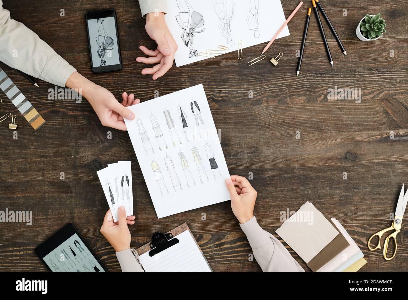 Hands of creative designer passing paper with drawn sketches to ...