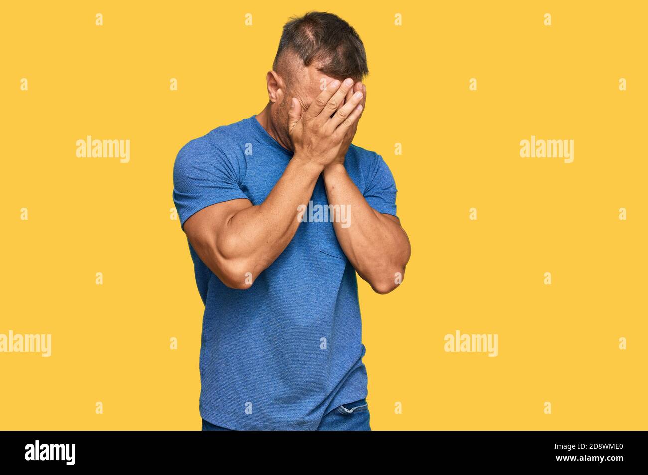 Handsome muscle man wearing casual clothes with sad expression covering ...